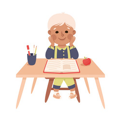 Cute boy sitting at the desk and reading a book Vector Image